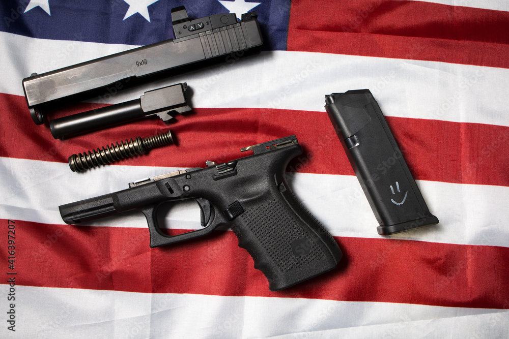 Closeup of a disassembled pistol on the American flag. Gun laws in the ...