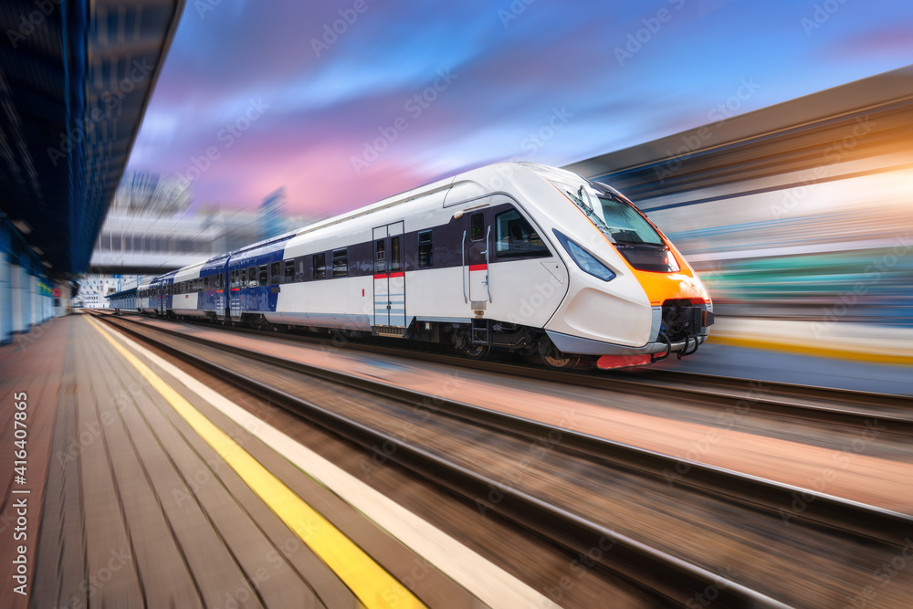 High speed train in motion on the railway station at sunset. Modern ...