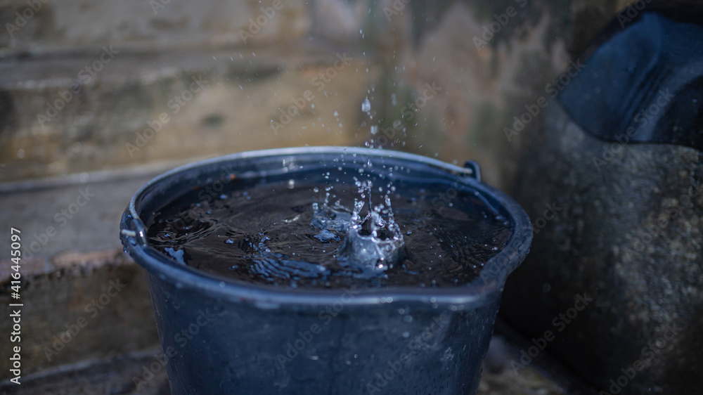 Rainwater shooting from a roof into a water collecting black plastic ...