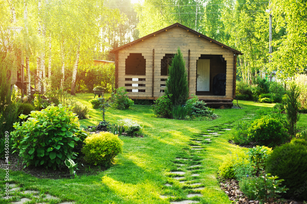 small wooden country house view in summer. Stone pathway, green lawn ...
