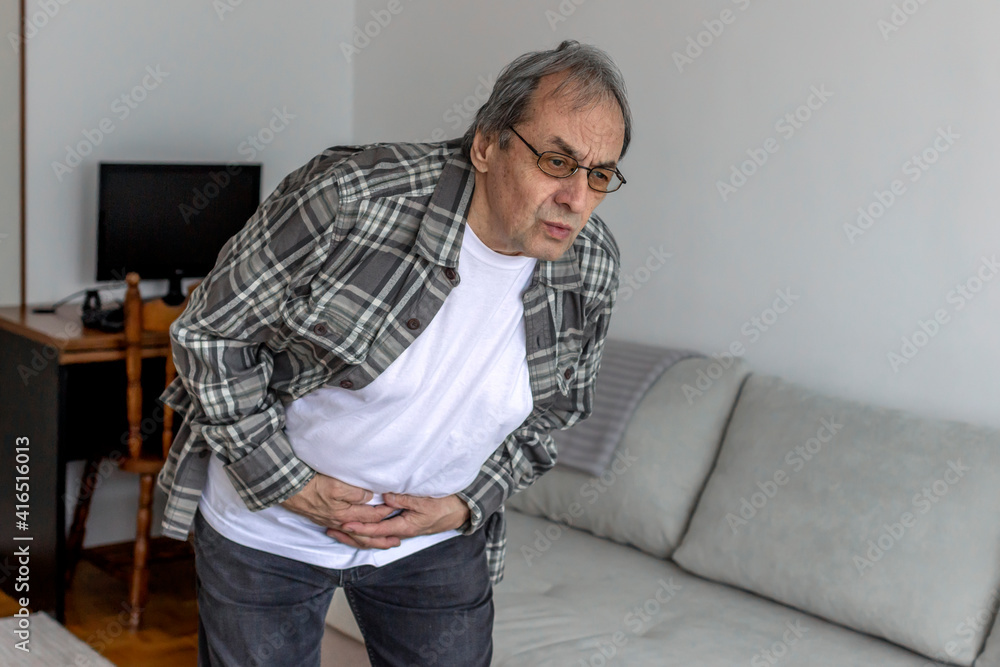 Mature Caucasian gray hair man stomach ache, pressing on stomach with ...