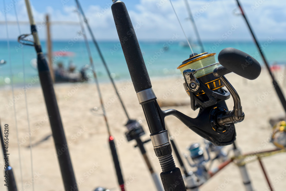 Foreground fishing rod and reel facing the sea, in the background the ...