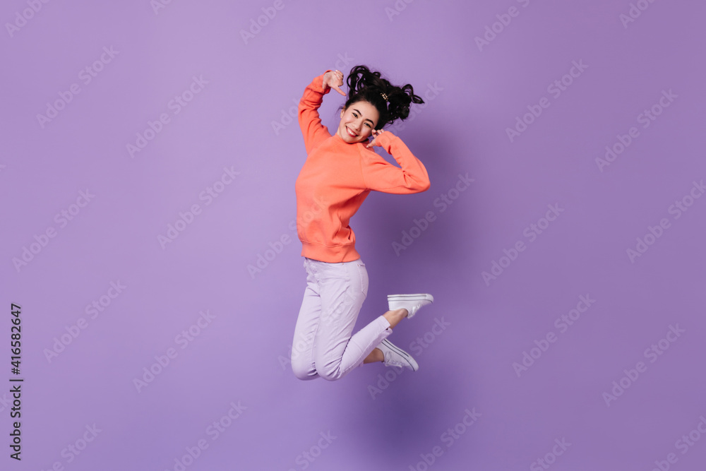 Pleased japanese girl jumping on purple background. Studio shot of ...