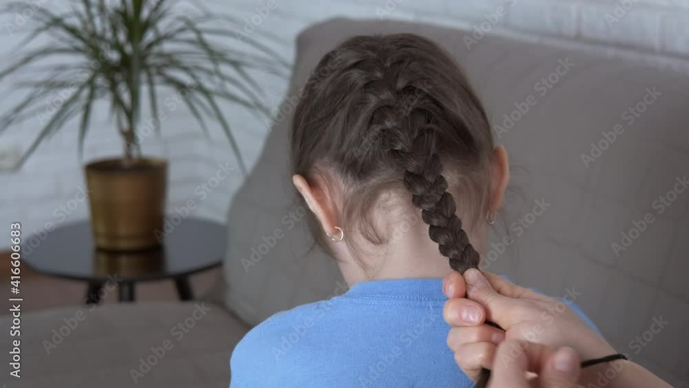 Father braids daughter. Father's hands are braiding little daughter's ...