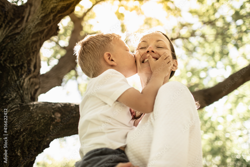 Child giving mother a kiss on the cheek. Family and happy childhood ...