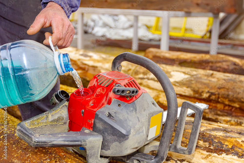 Carpenter pours gasoline from a plastic bottle into a chainsaw Stock ...