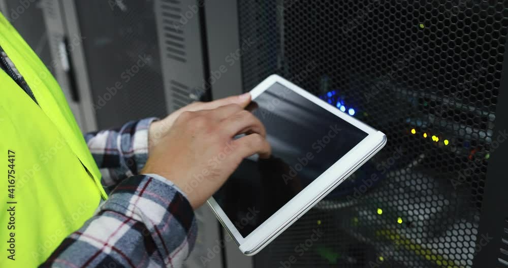 Technician man holding digital tablet while examining server in server ...