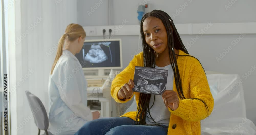 Happy pregnant black woman showing sonogram picture at camera sitting ...