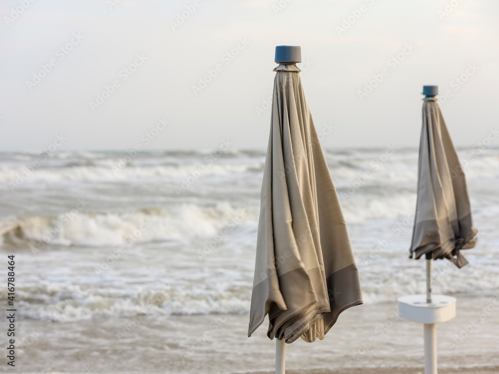Parasols closed due to strong wind on a late summer day with rough seas ...