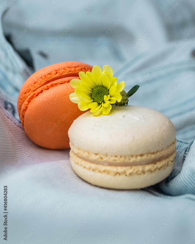 Beige and orange macaroons on a blurry denim background with a yellow ...