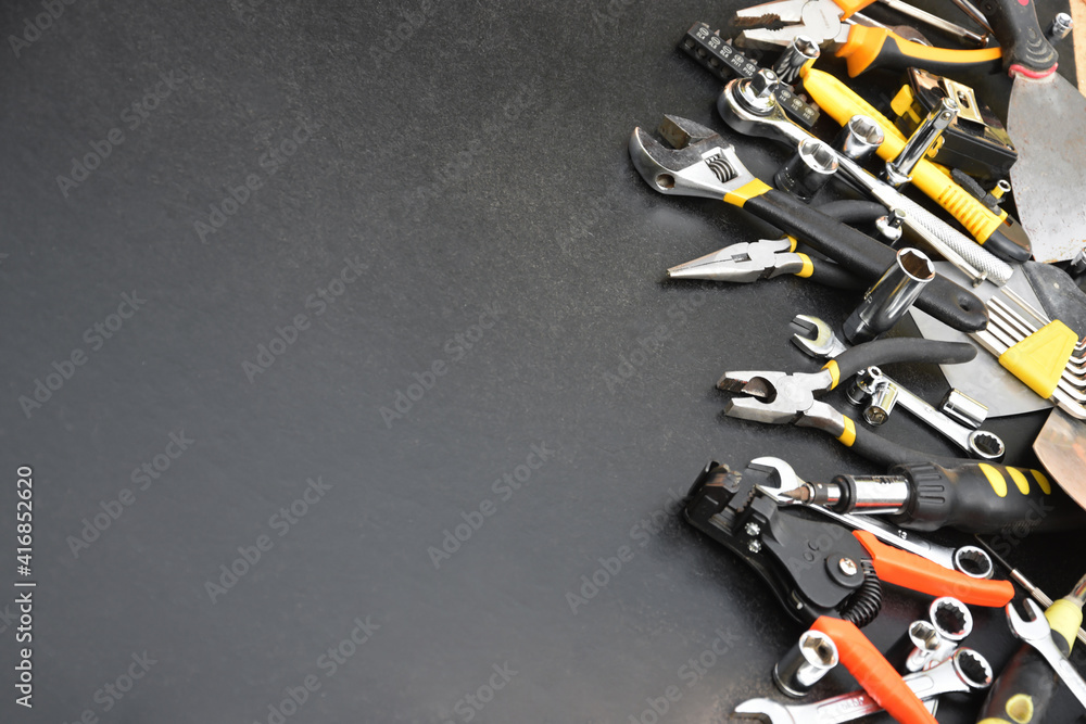 Handyman tool kit on black wooden table. Many wrenches and screwdrivers ...