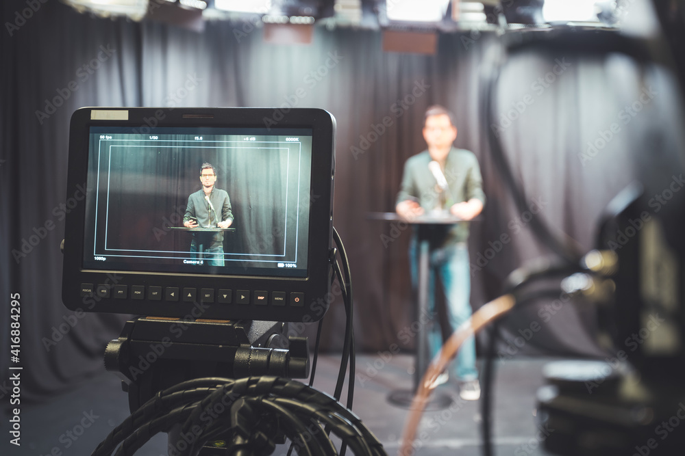 Young journalist in a television recording studio is talking into a ...