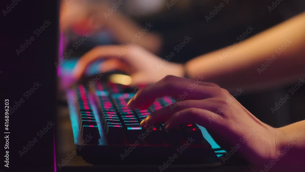A close-up gamer's hands are using the keyboard and mouse. The ...