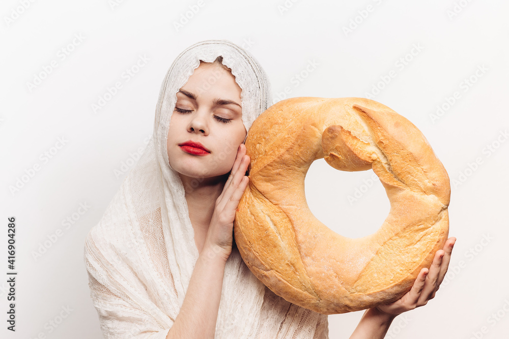 beautiful woman with a round loaf of bread in her hands on a light ...