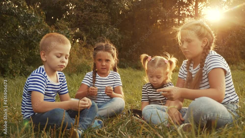 group of children are sitting in the park on the grass talking. kid ...