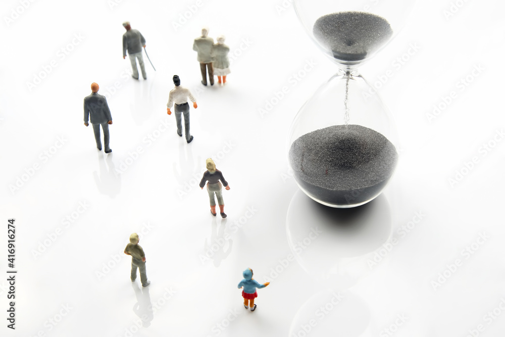 miniature people. different people are walking next to the hourglass on ...