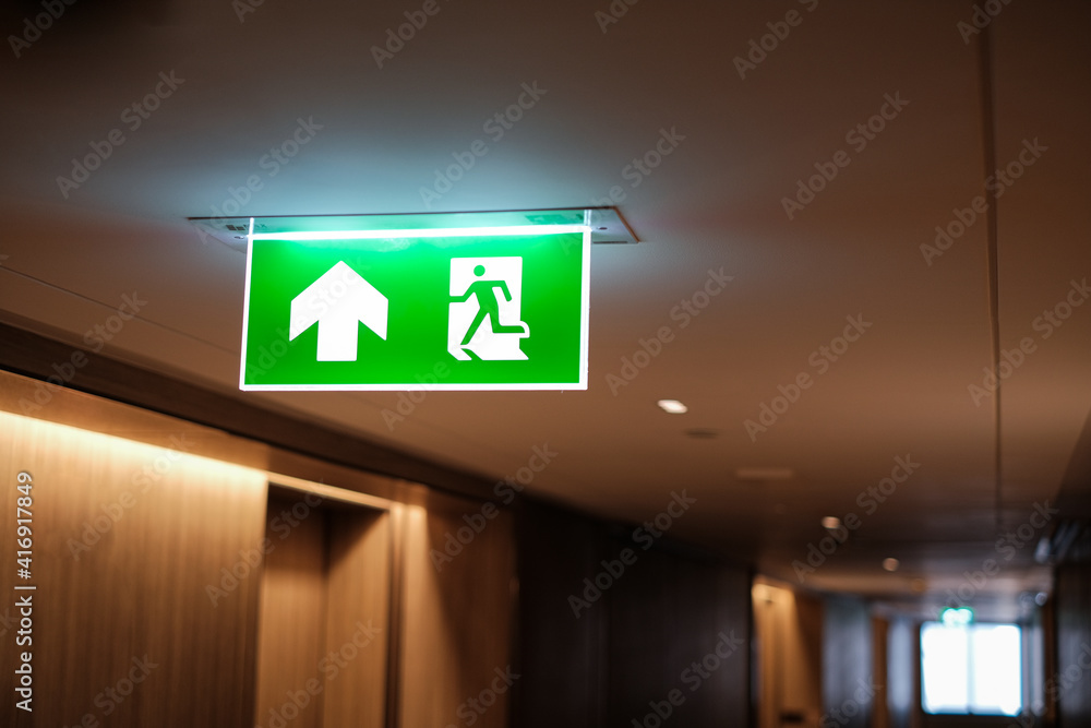 Emergency exit sign at the corridor in building. Green fire exit sign ...