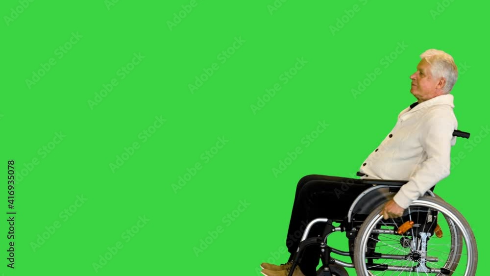 Disabled senior gentleman riding by on a wheelchair on a Green Screen ...