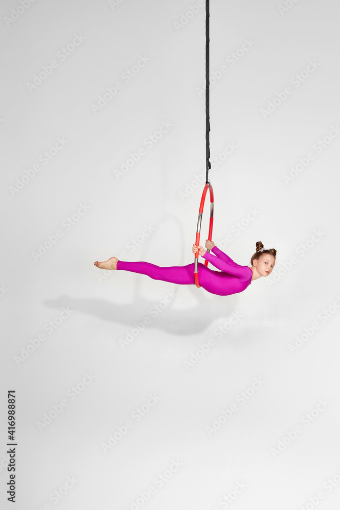 Foto de little child girl gymnast in pink sportwear shows an acrobatic ...