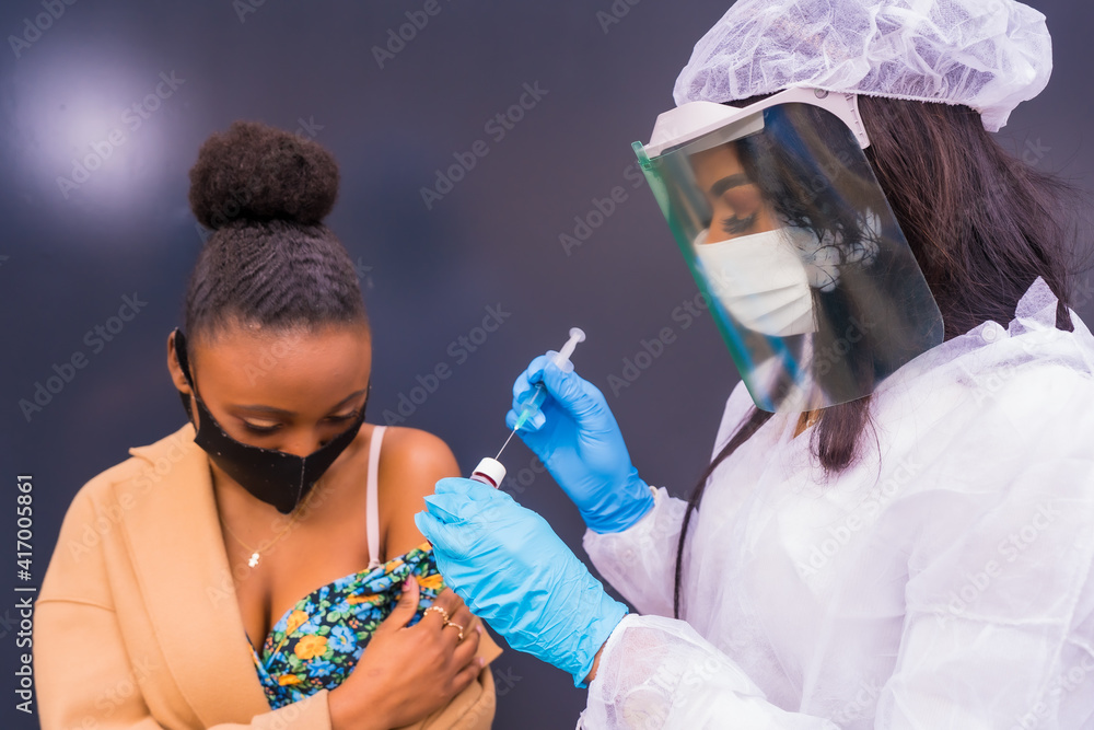 Black woman receiving the injection of the coronavirus vaccine by a ...
