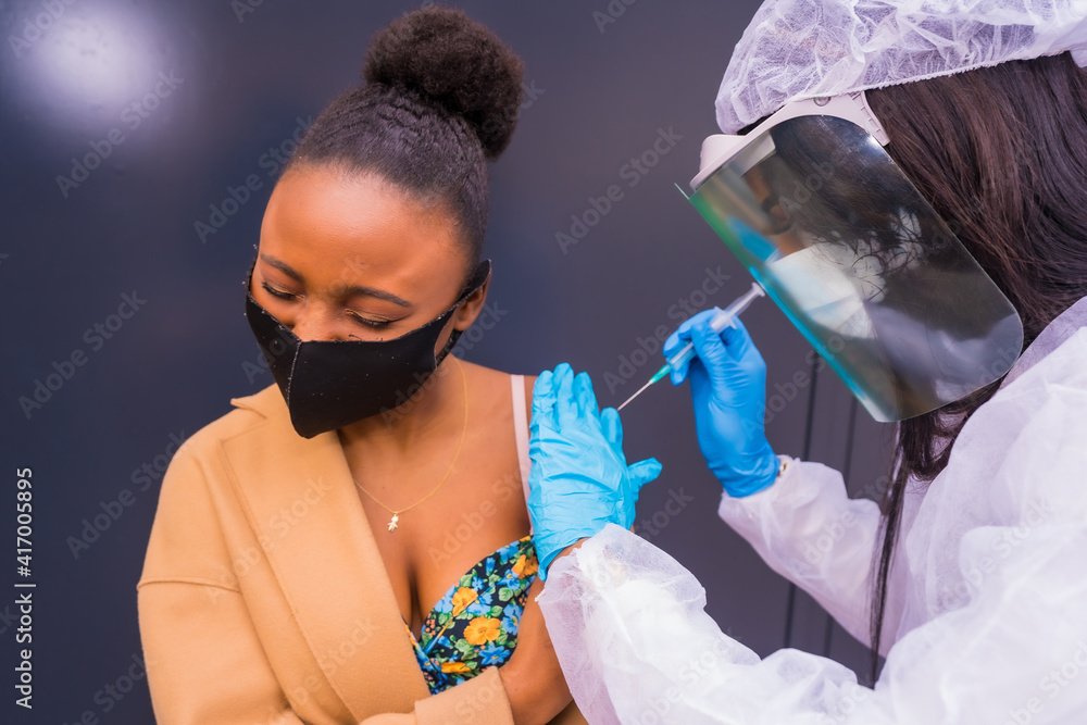 Young black girl receiving the injection of the coronavirus vaccine by ...