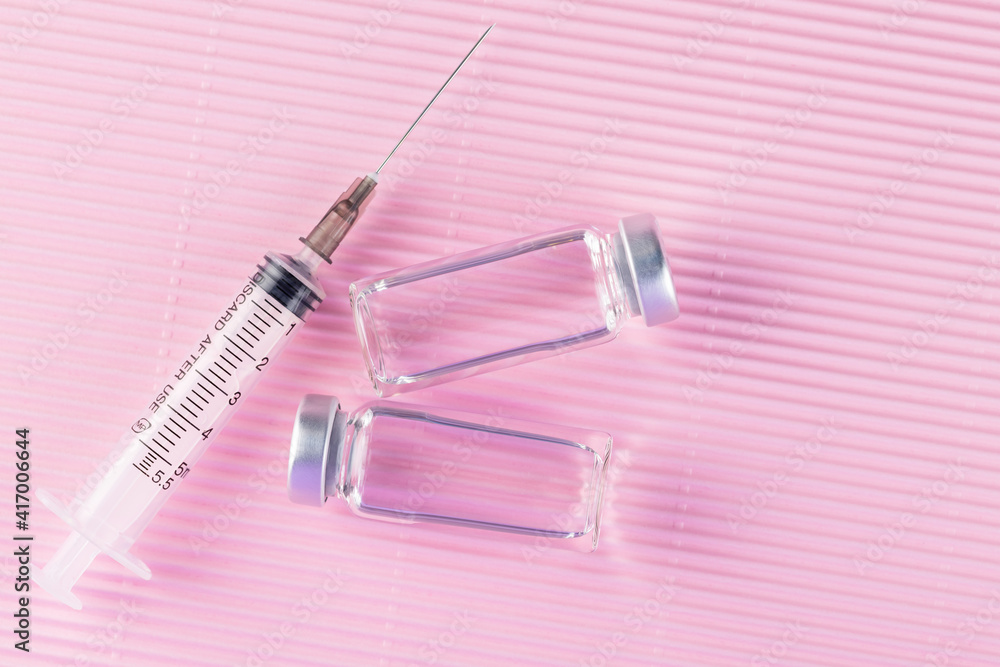 Healthcare cure concept with vaccine and syringe injection. Vaccines and syringe on a pink ...