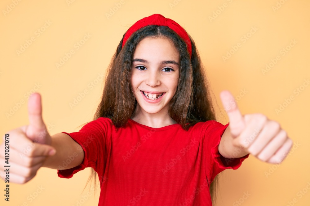 Cute hispanic child girl wearing casual clothes and diadem approving ...
