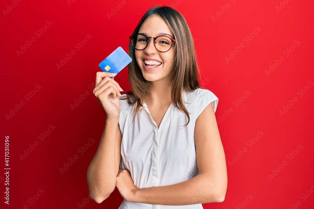 Foto de Young brunette woman holding credit card smiling and laughing ...