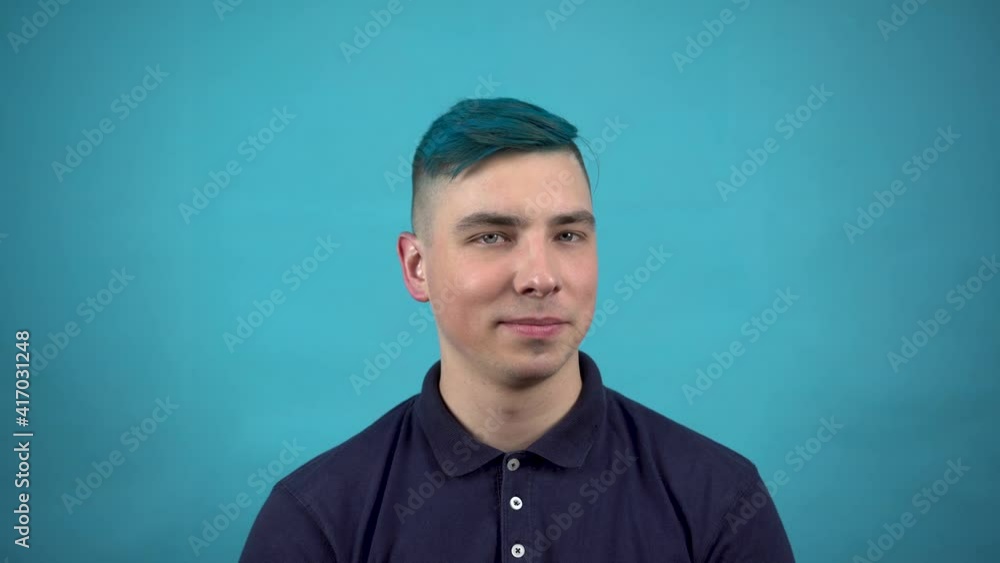 A young man in glasses with blue hair winks at his eyes. Emotional man ...