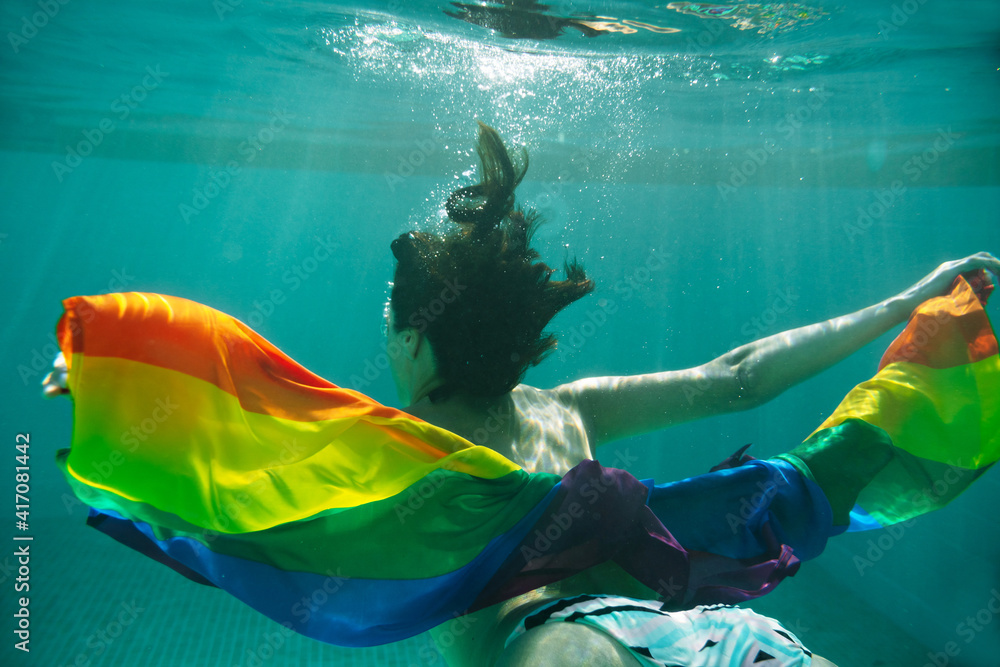 Horizontal view of unrecognizable woman swimming underwater holding a ...