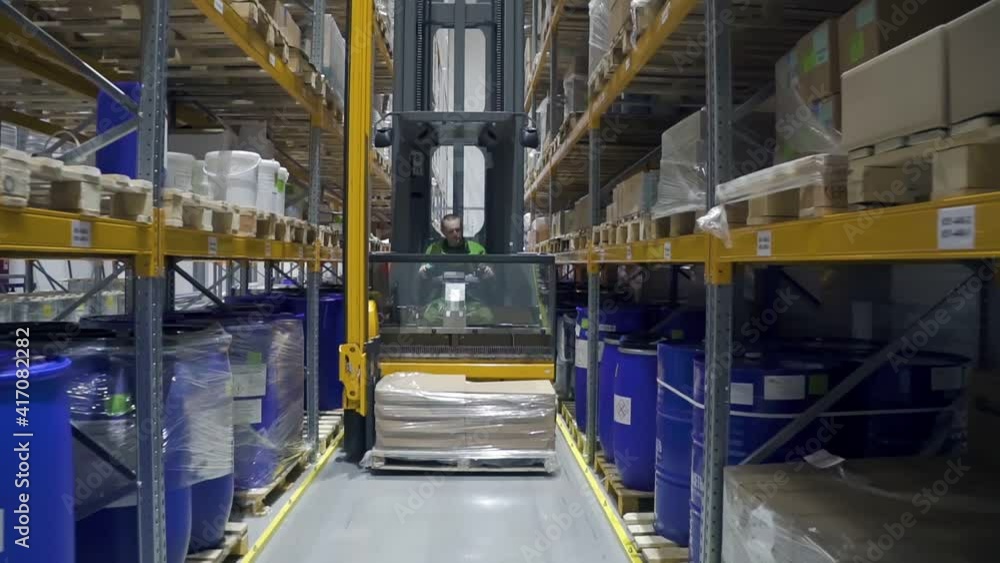 Warehouse male worker with forklift. loader lifting goods at shelves ...
