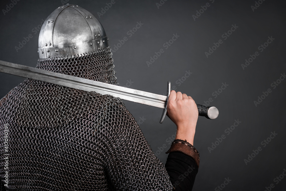 Back view of a knight in chain mail and a helmet with a sword on his ...