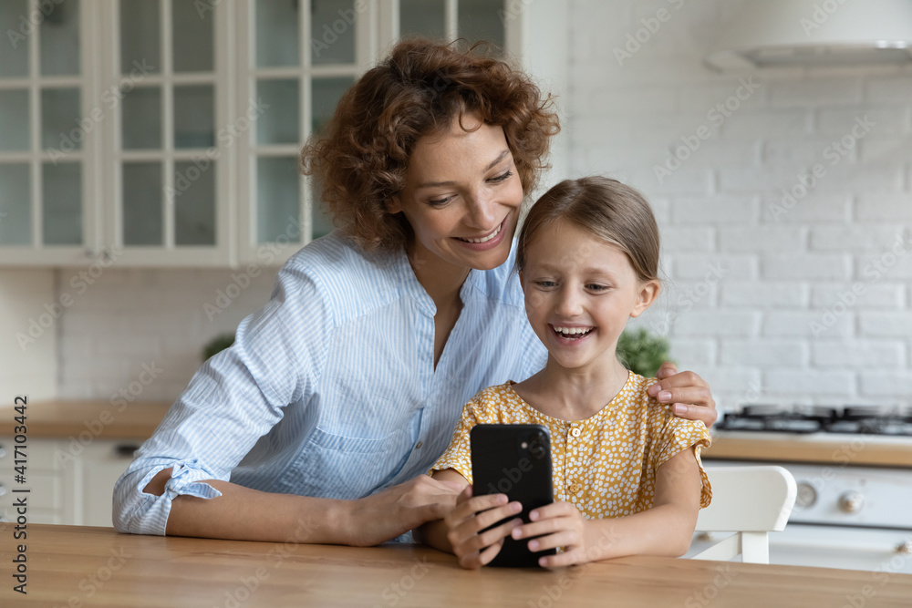 Look, mommy. Interested young mom sit by table hug shoulders of beloved ...