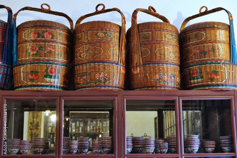 Antique painted and woven bamboo baskets atop a display case in a dimly ...