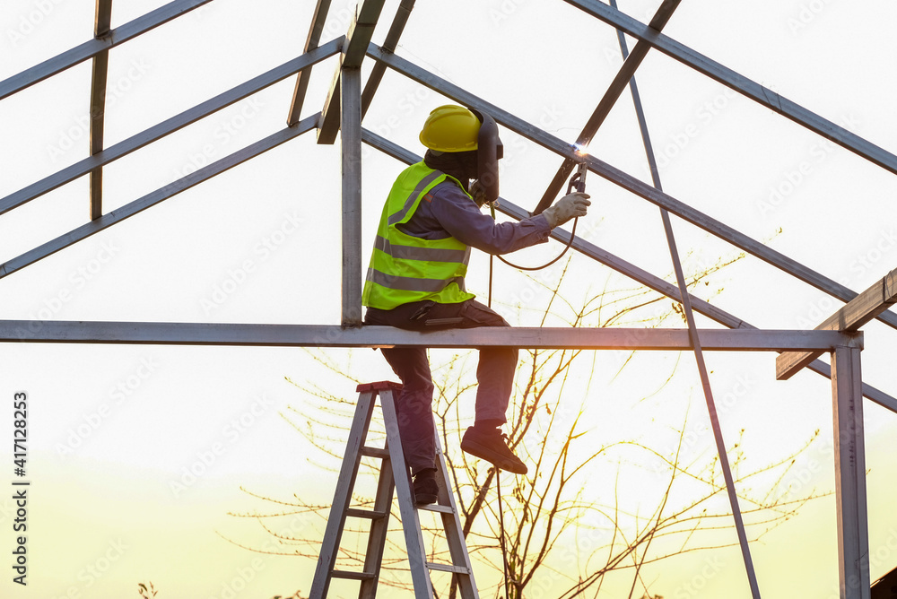 Roofing workers working on roof trusses on a construction site are ...