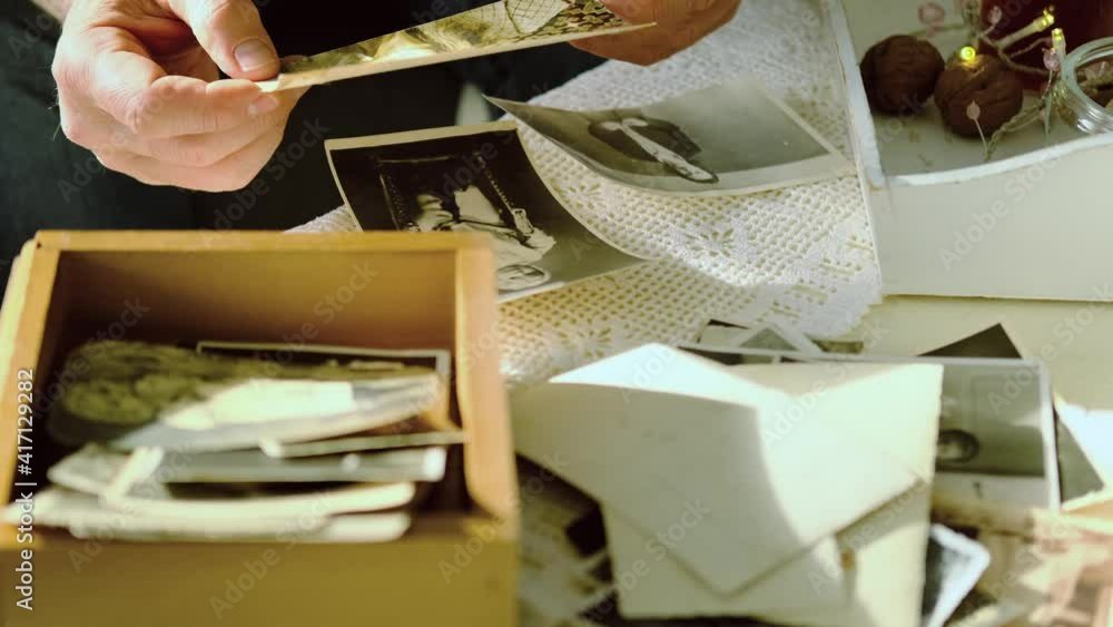 elderly man looks through an album with old photographs of 1970 ...