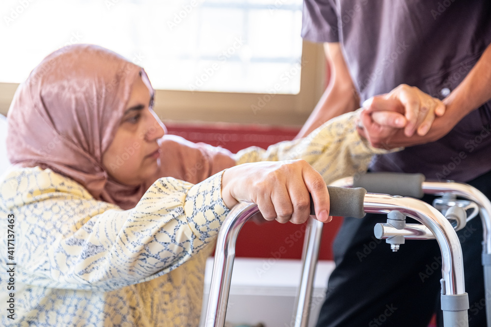muslim woman with disability is trying to stand with her son's help ...