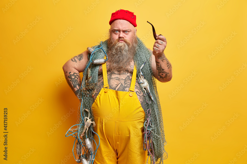 Angry irritated bearded boatswain looks with sullen expression directly ...