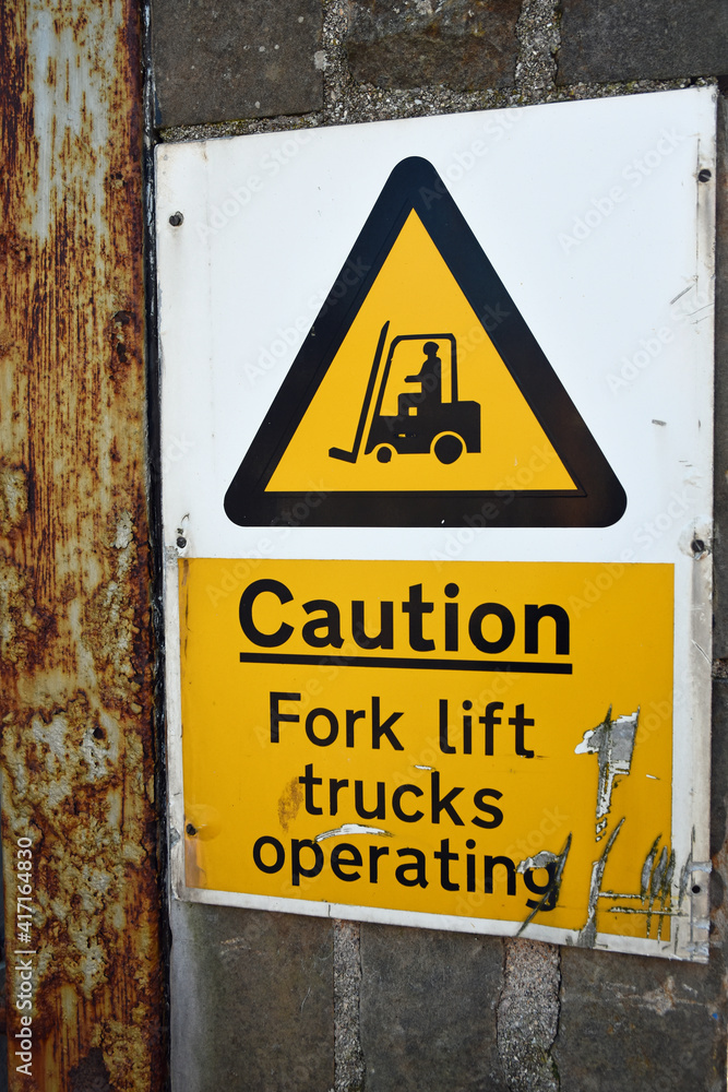 Caution fork lift trucks operating sign with industrial wall background ...