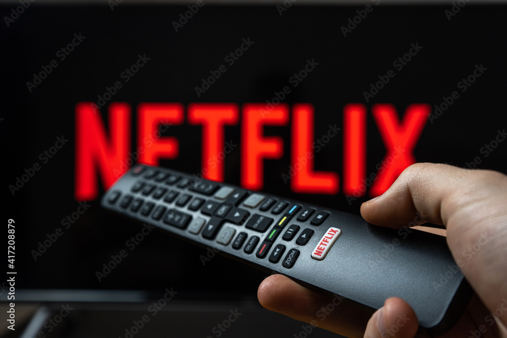 Holding TV remote controller with Netflix logo. Turning on Netflix ...