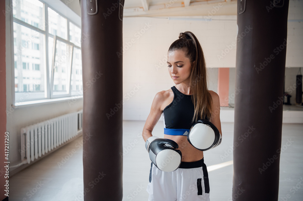 Female athlete boxing the punching bag in urban industrial gym Stock ...