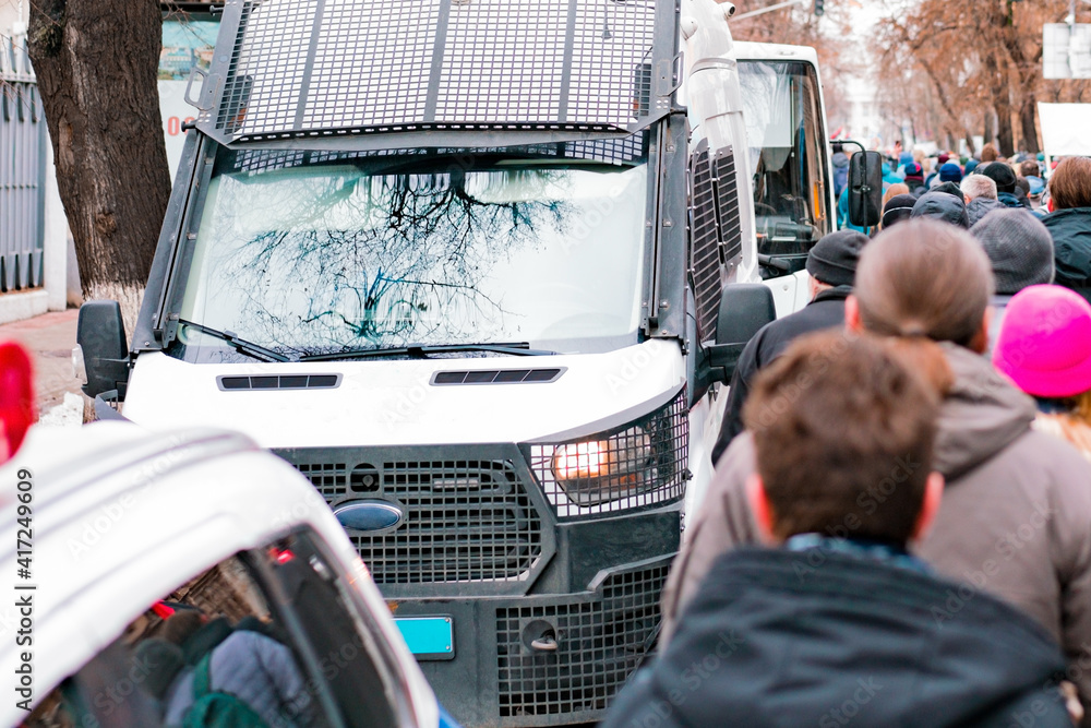 Crowd on the street going through new armoured bus with steel sliding ...