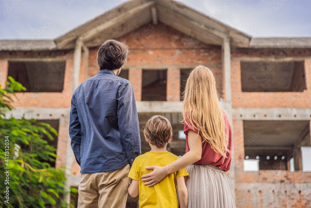 Family mother, father and son looking at their new house under construction, planning future and ...