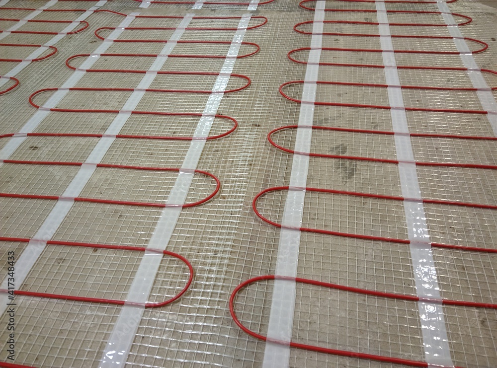 Closeup of concrete and red electrical wires. Electric floor heating ...