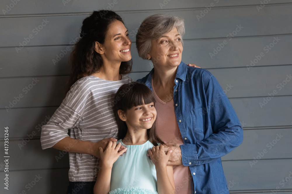 Happy three generations of Latino women isolated on grey wall look in ...
