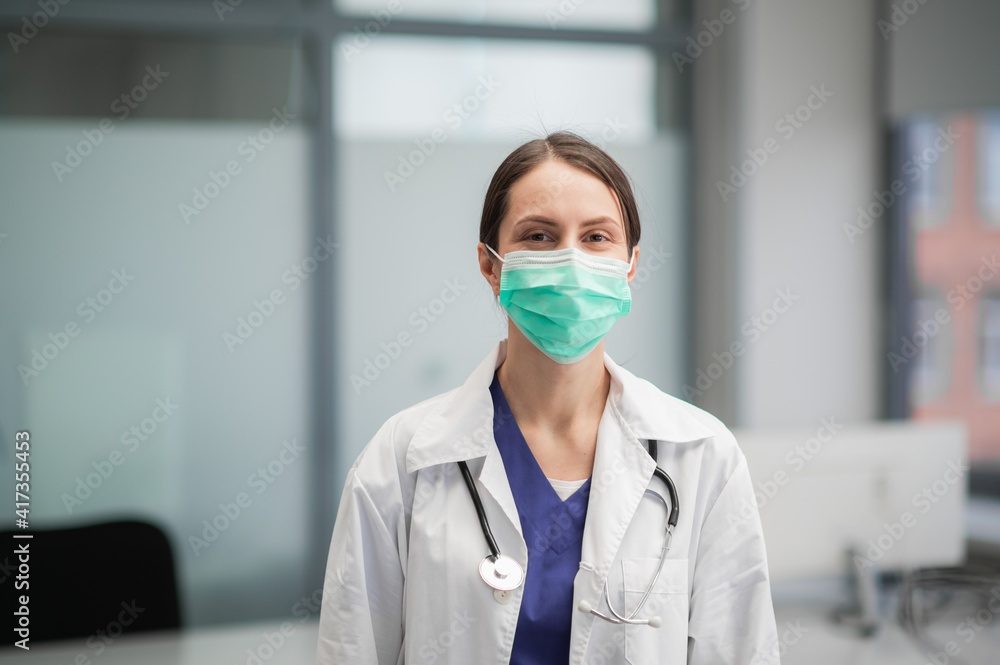 Cute female doctor poses for a photo, looks at the camera in a mask ...