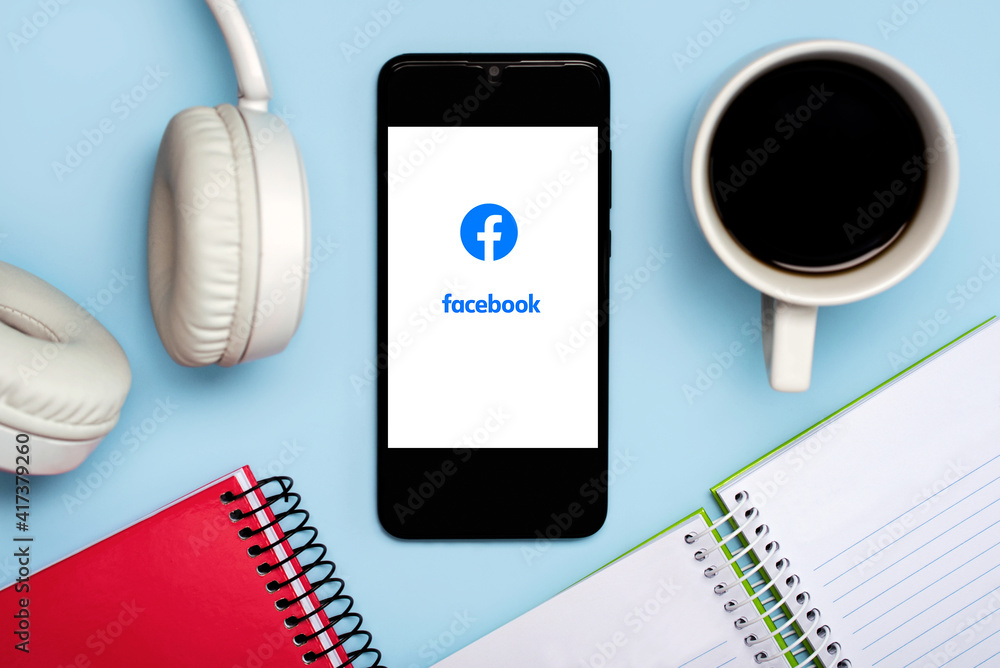 Facebook logo on white screen of smartphone with notebooks,headphone ...