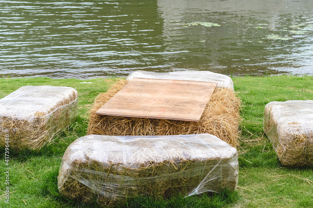 Seats and tables made from straw bales for event and party laid on lawn ...