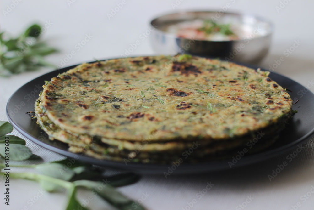 Whole wheat methi thepla rolls with paneer capsicum filling and a bowl ...