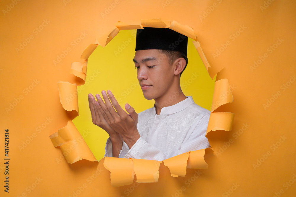 Muslim man praying through the torn yellow paper hole, wearing Muslim ...